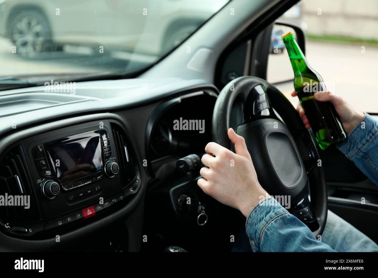 Man with bottle of beer driving car, closeup. Don't drink and drive ...