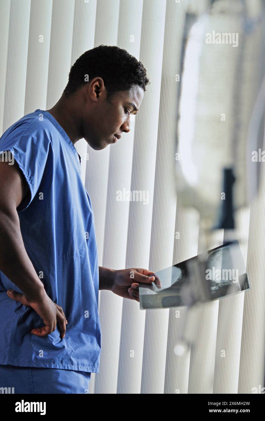 A male african-American surgeon in scrubs is carefully studying the ...