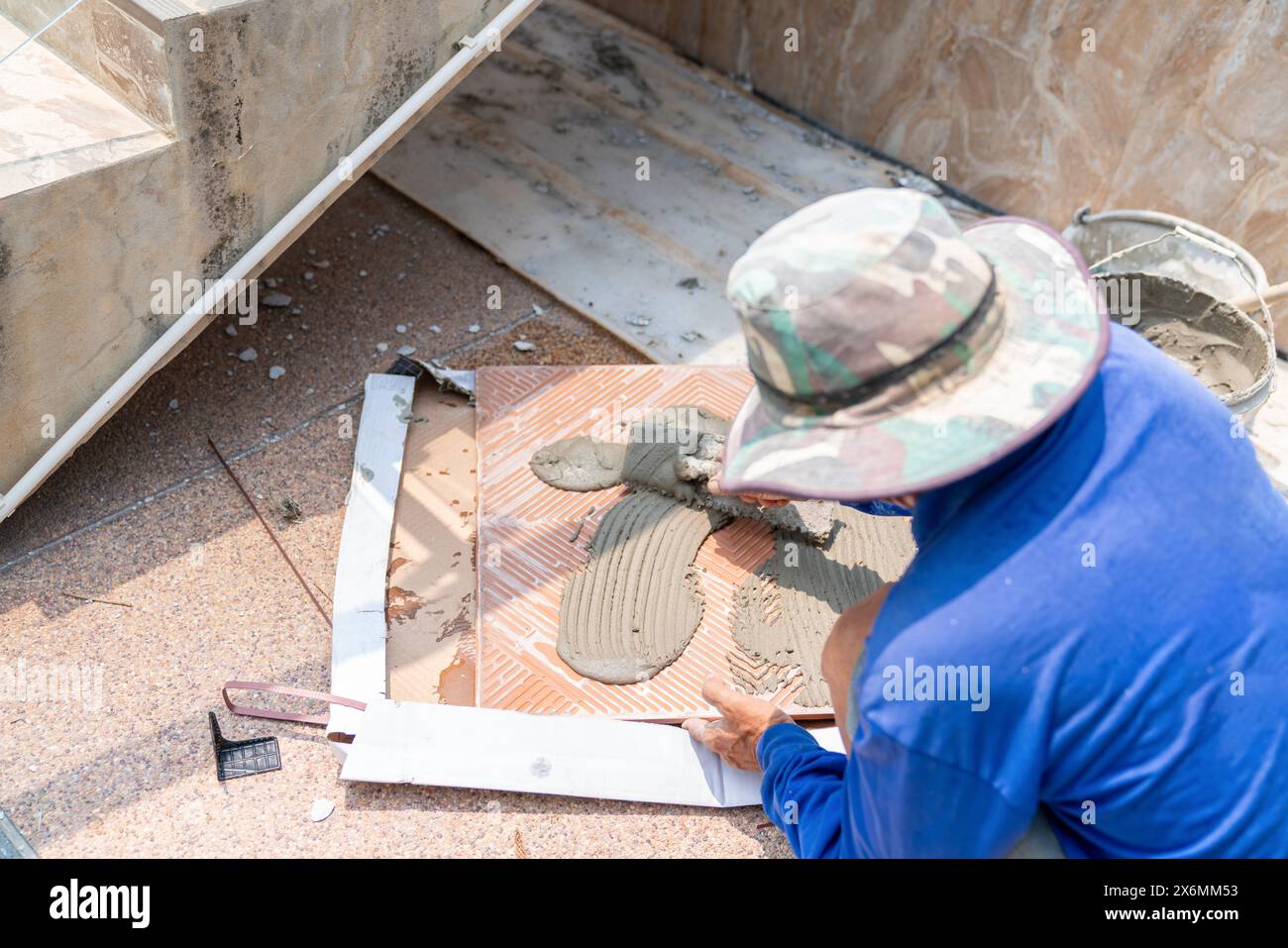 Worker tile mason spreading adhesive on tile for tiling wall Stock ...
