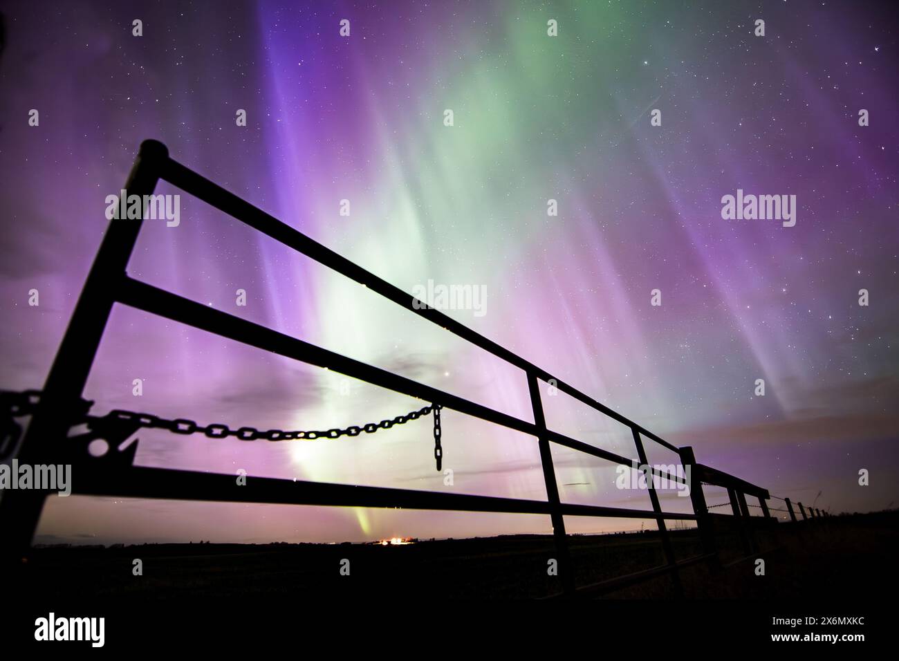 Aurora Borealis dancing across the night sky with a metal gate ...
