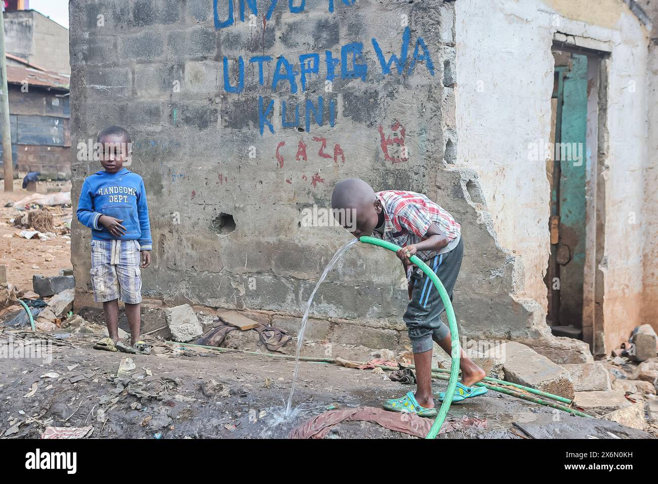 Two Local children quench their thirst with burst water pipe near ...