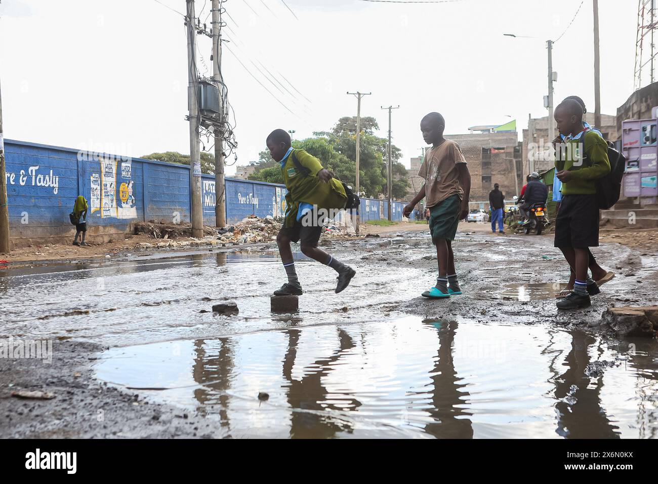 Kenyan school children jump over stagnant water near the Mathare North ...