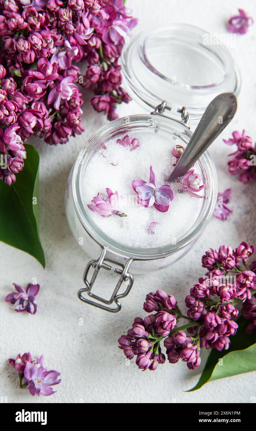 A clear glass jar with a silver clasp is filled with homemade lilac ...