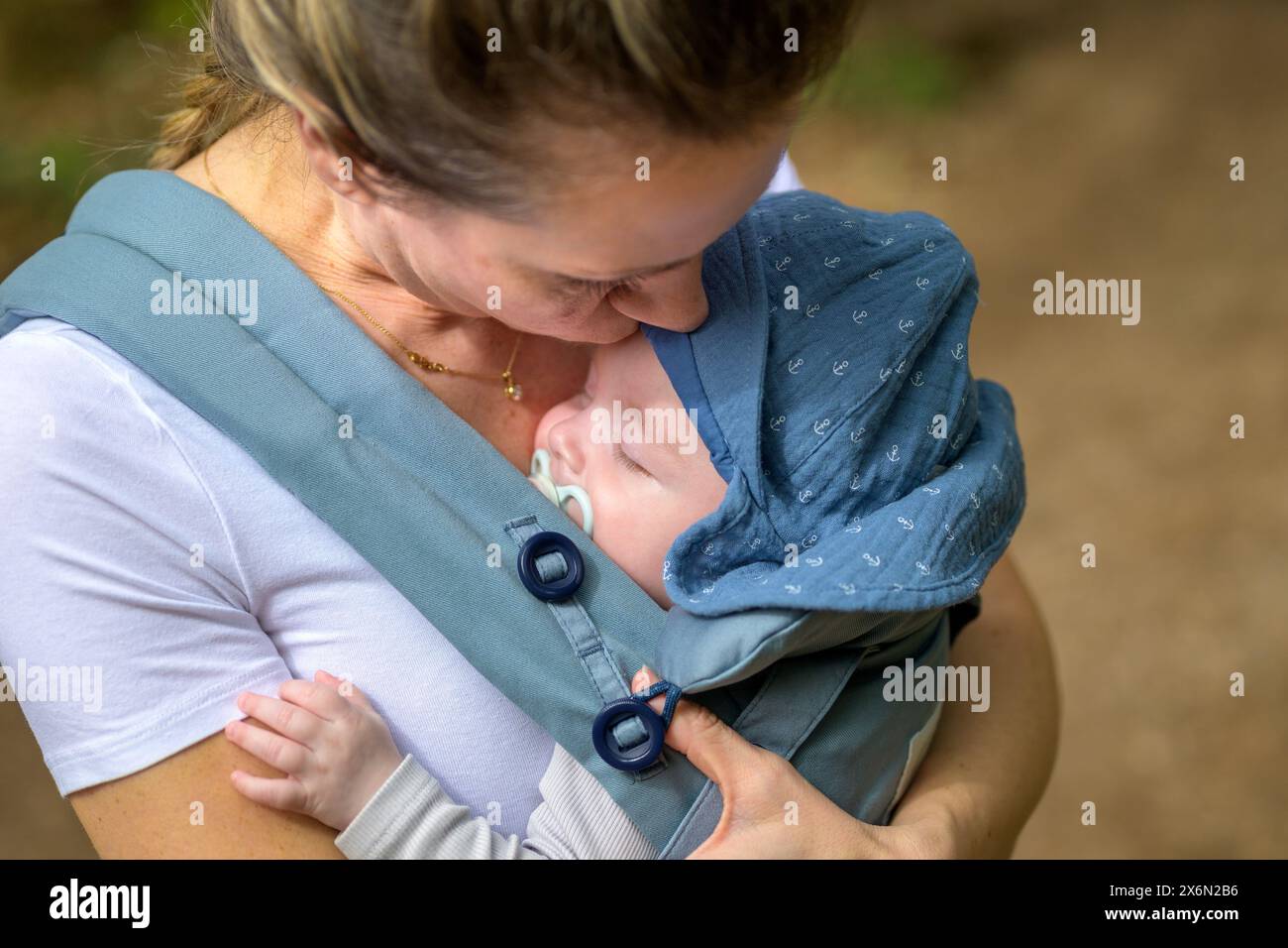 Extreme close up of a baby sleeping in a baby carrier on his mother's ...