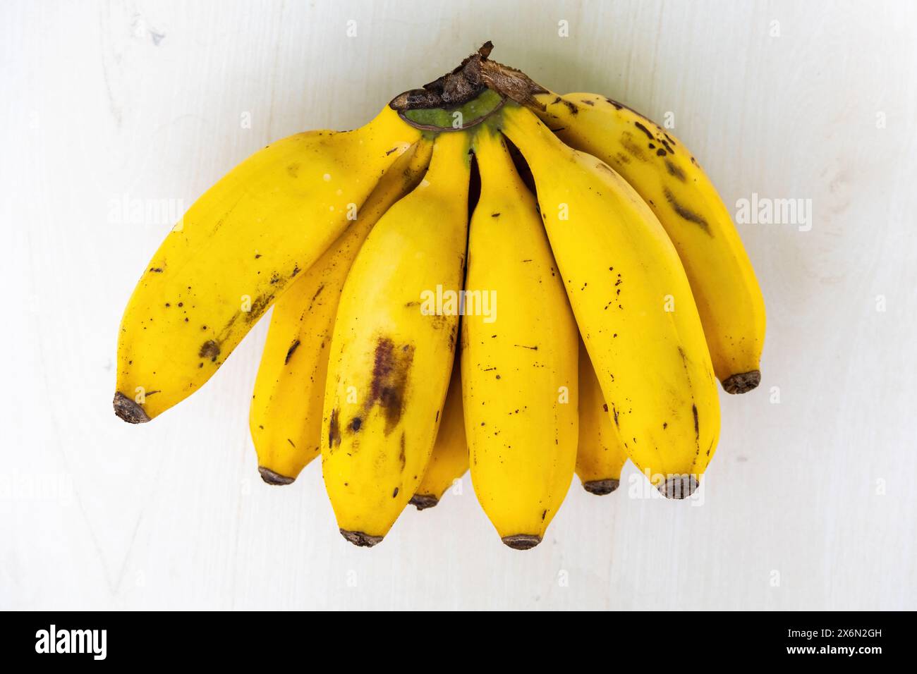A bunch of fresh ripe yellow bananas on wooden textured white ...