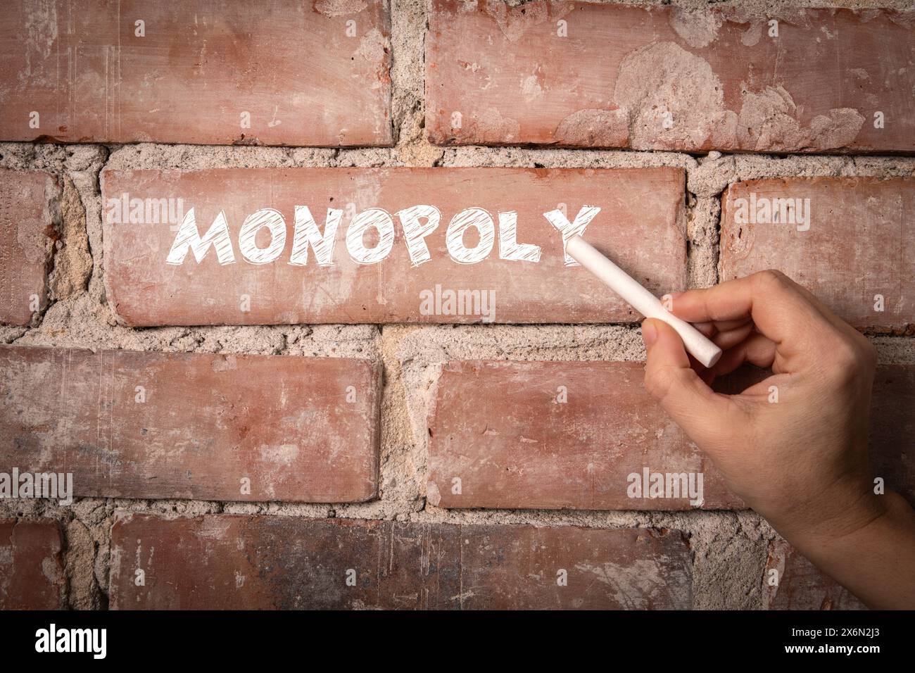 Monopoly. Text written with white chalk on a red brick background Stock ...