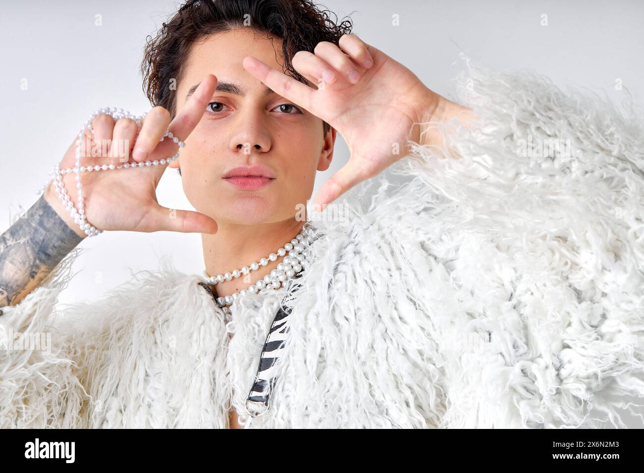 young brunette hispanic gay man with natural make up looking at camera ...