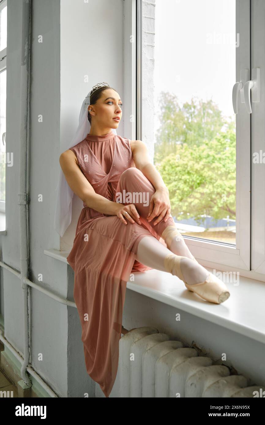 Ballerina sits thoughtfully on the windowsill and looks out the window during a break Stock ...