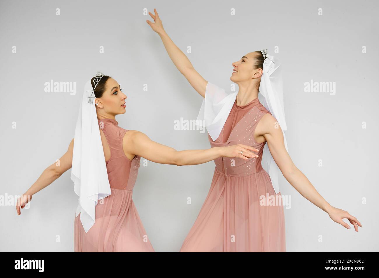 Two ballerinas in peach dress waving hands in front of each other on ...