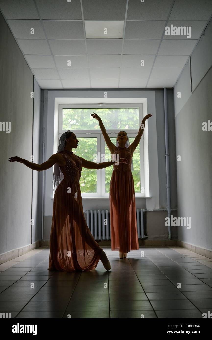 Silhouette of two female dancers rehearsing choreography in the hallway ...