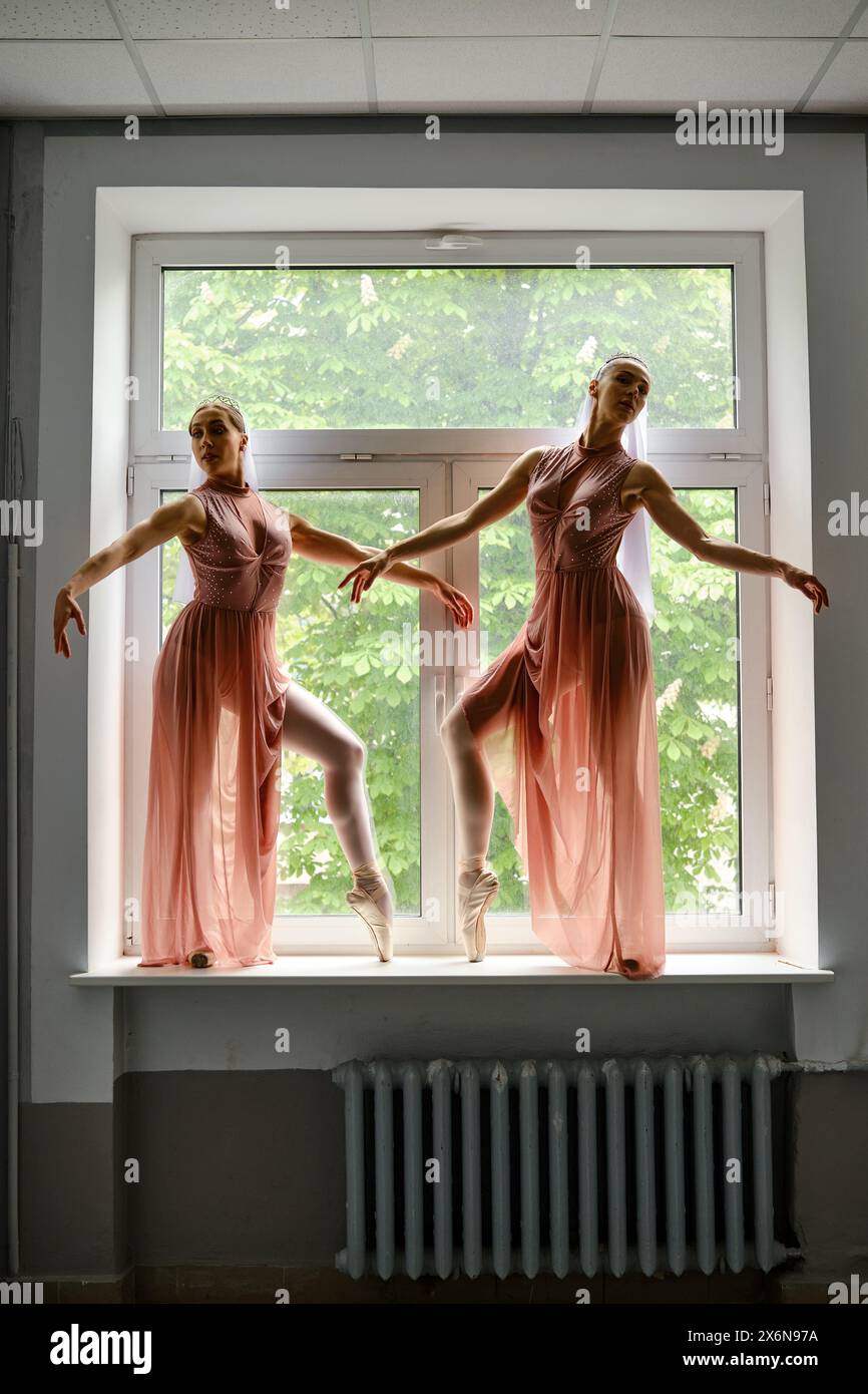 Silhouette of two ballerinas perform dance moves while standing on a ...
