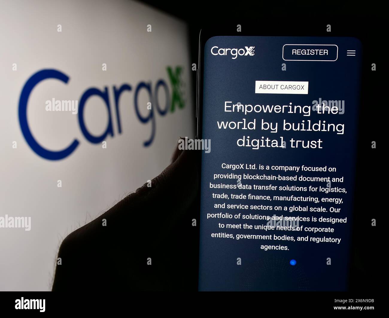 Person holding cellphone with webpage of Slovenian blockchain technology company CargoX Ltd. in ...