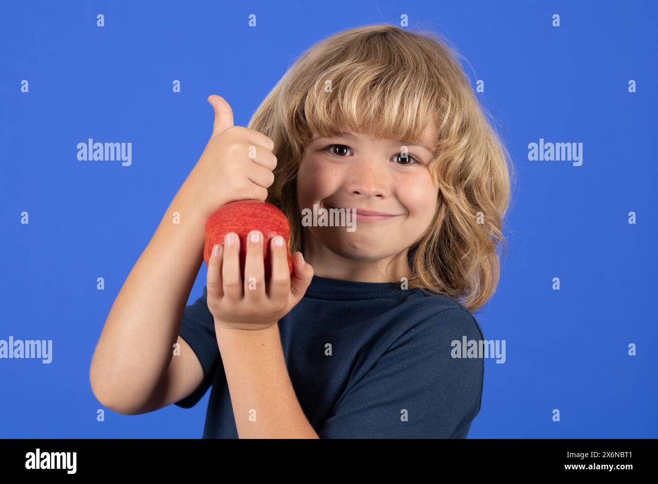 Healthy eating. Kid with thumbs up eating apple. Portrait of of cute ...