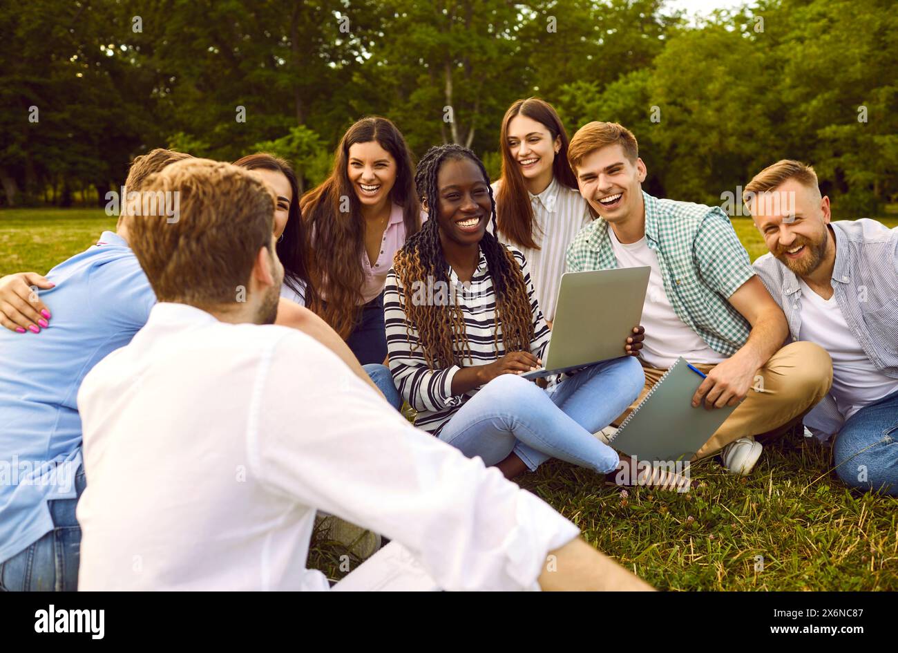 Group of happy college friends studying together outdoors and laughing ...
