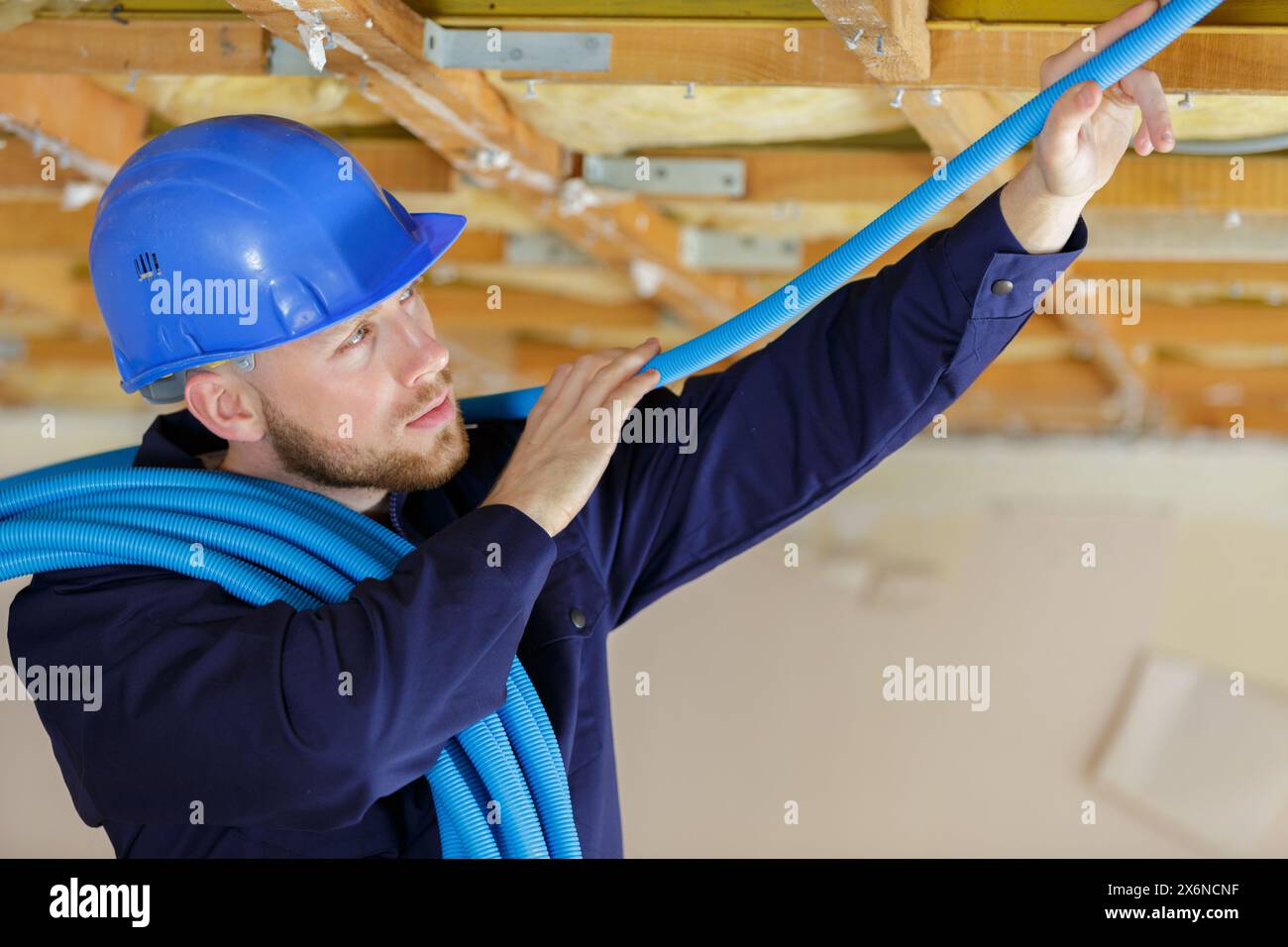builder installing blue ducting between roof joists Stock Photo - Alamy