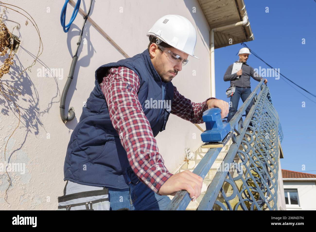 man sanding exterior handrail Stock Photo - Alamy