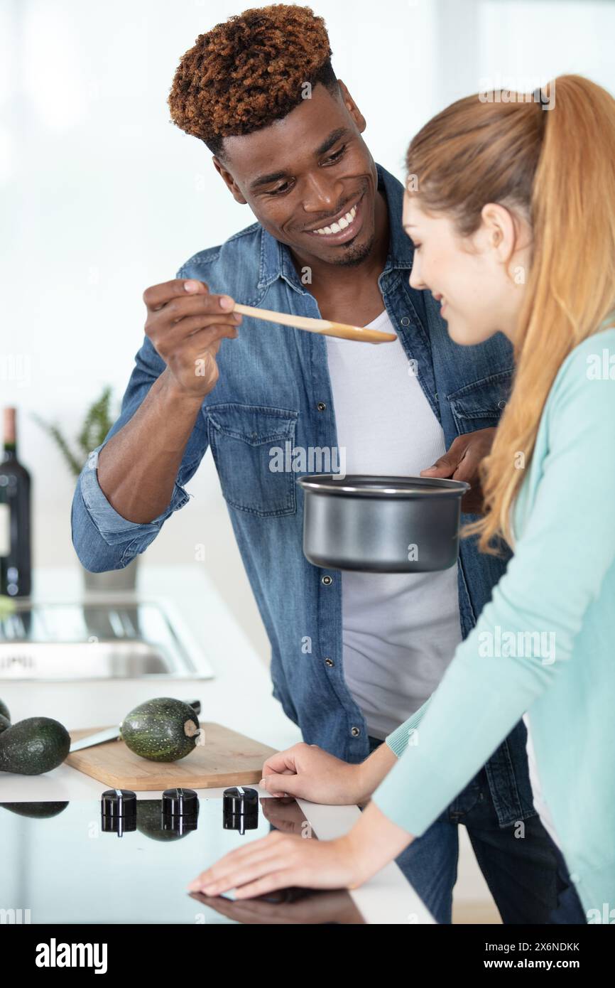 man offering his girlfriend to taste food on wooden spoon Stock Photo ...