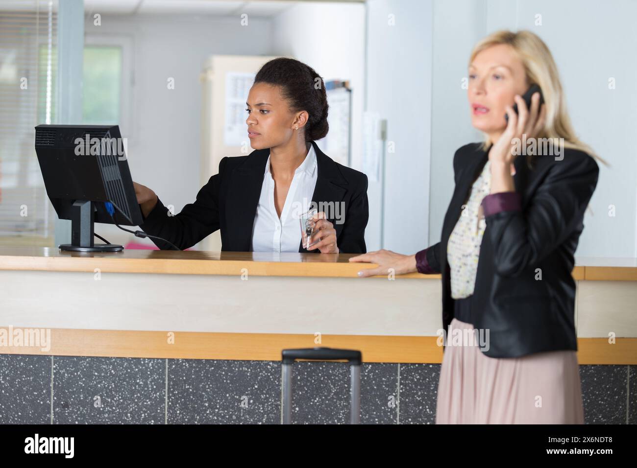female client on telephone stood at hotel reception Stock Photo - Alamy