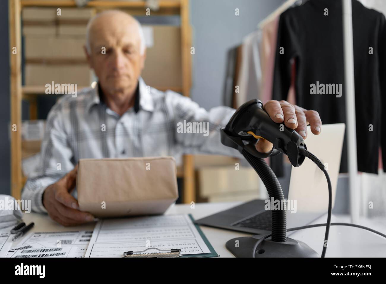 Elderly male shop owner sitting in front of desk, using computer and ...