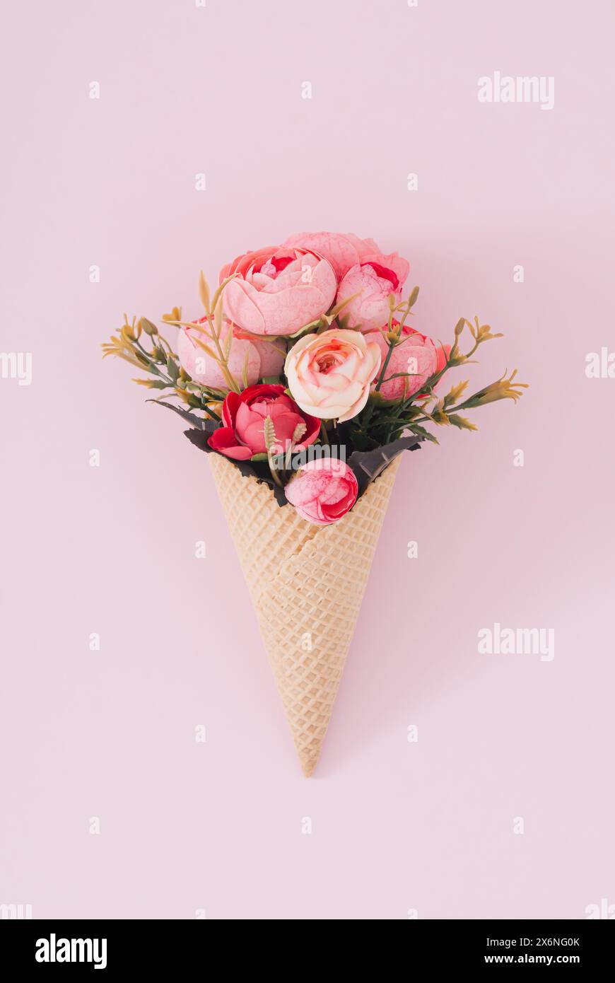 Ice cream cone with pink flowers and leaves on light pastel pink ...