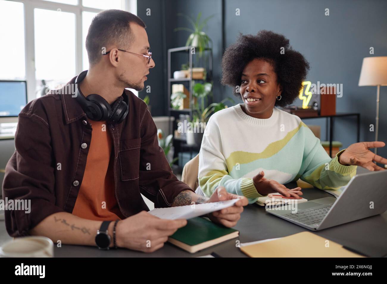 Portrait of two colleagues collaborating on project sitting at desk in ...