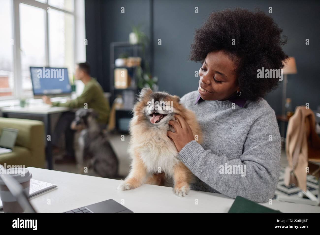 Portrait of smiling Black woman cuddling with cute little dog while ...