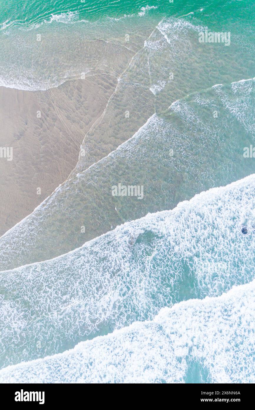 drone aerial top view of the foamy waves coming ashore at low tide ...