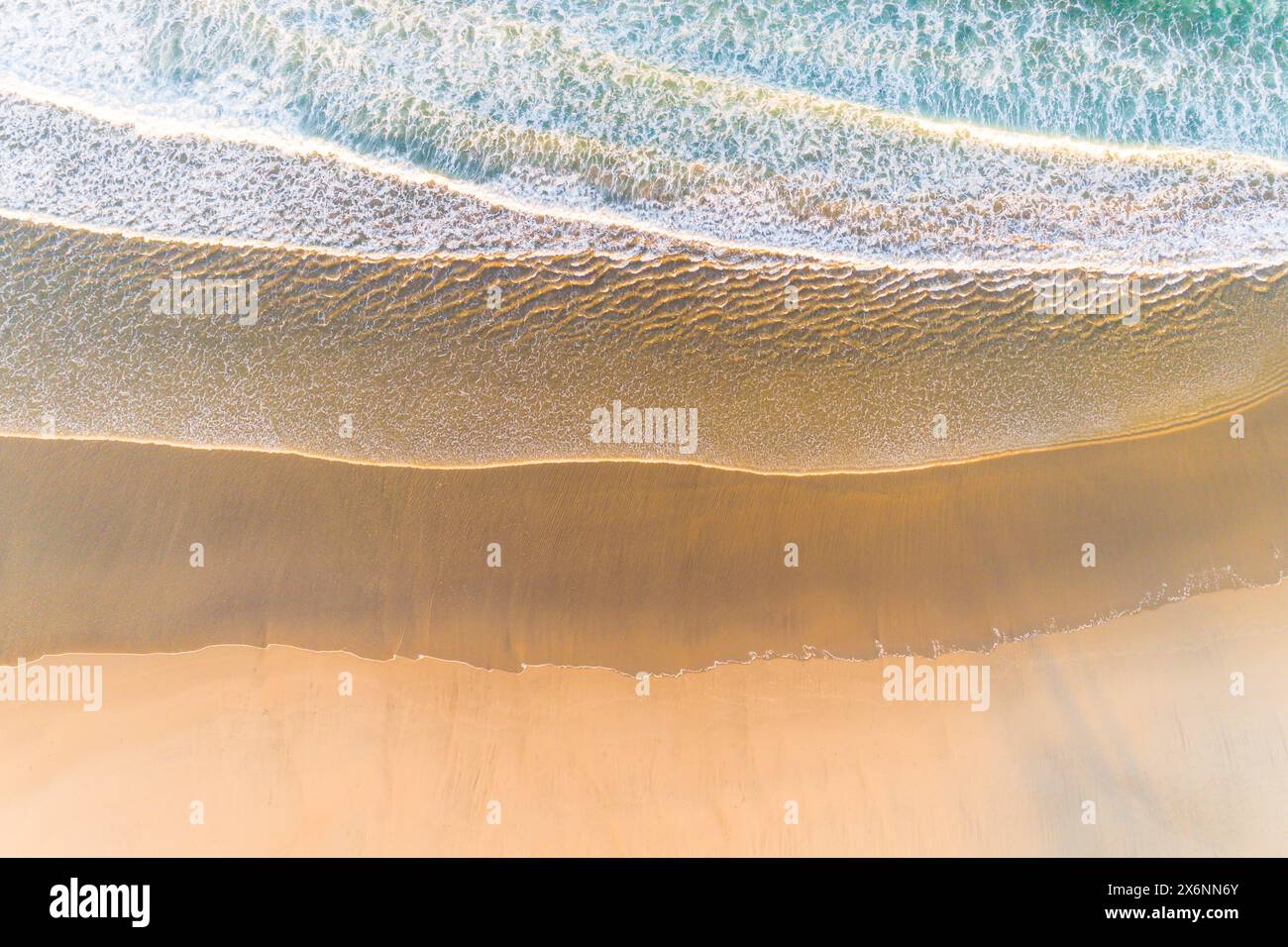 drone aerial overhead view of the foamy waves in the shore of a beach ...