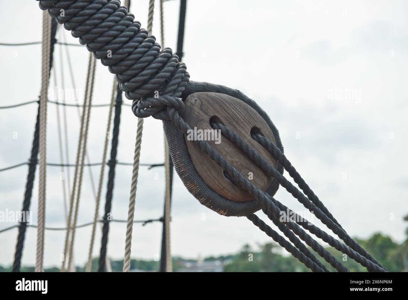 Wooden pulley and rigging ropes. Mayflower II replica ship moored at ...