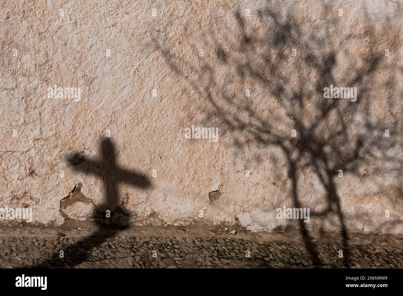 Shadow of a cross and a tree cast in black on an old stone building in ...