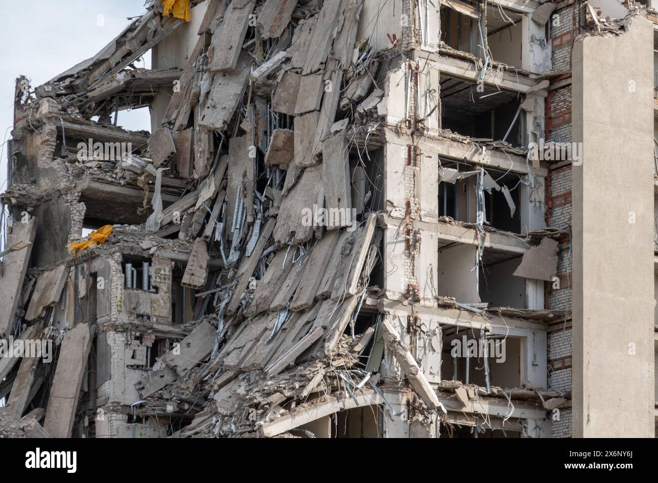 A detailed view of a partially collapsed building with visible damage, exposed floors, and ...