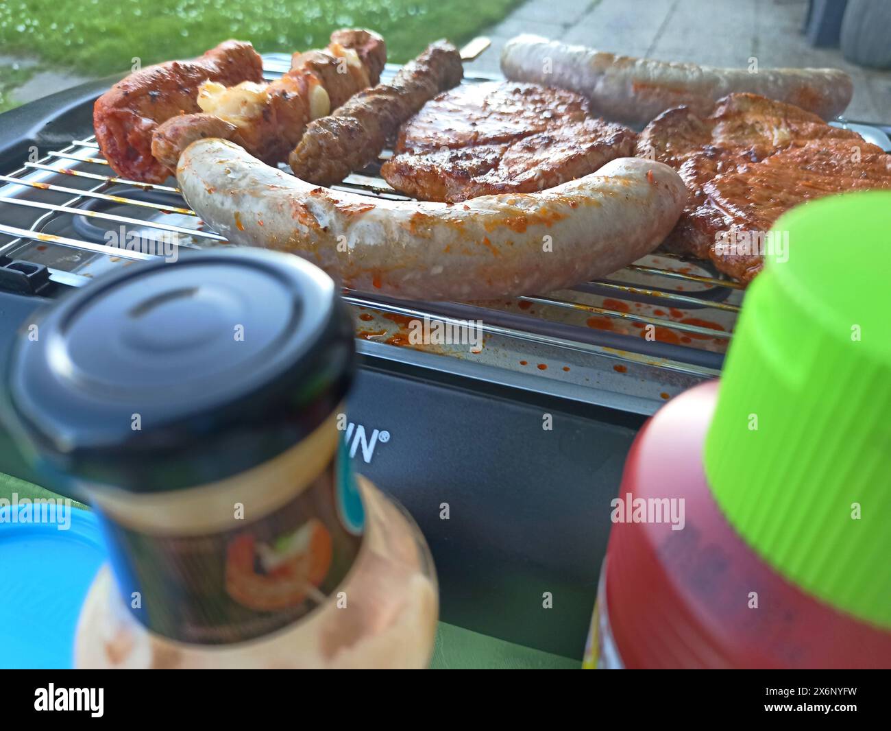Grillgut auf einem Tischgrill im eigenen Garten. Grillsaison 2024 ...