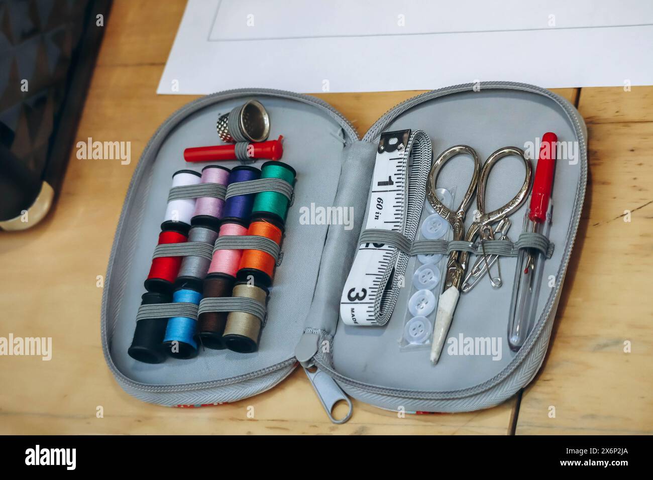 Sewing kit including colored thread, scissors, measuring tape, pins and ...