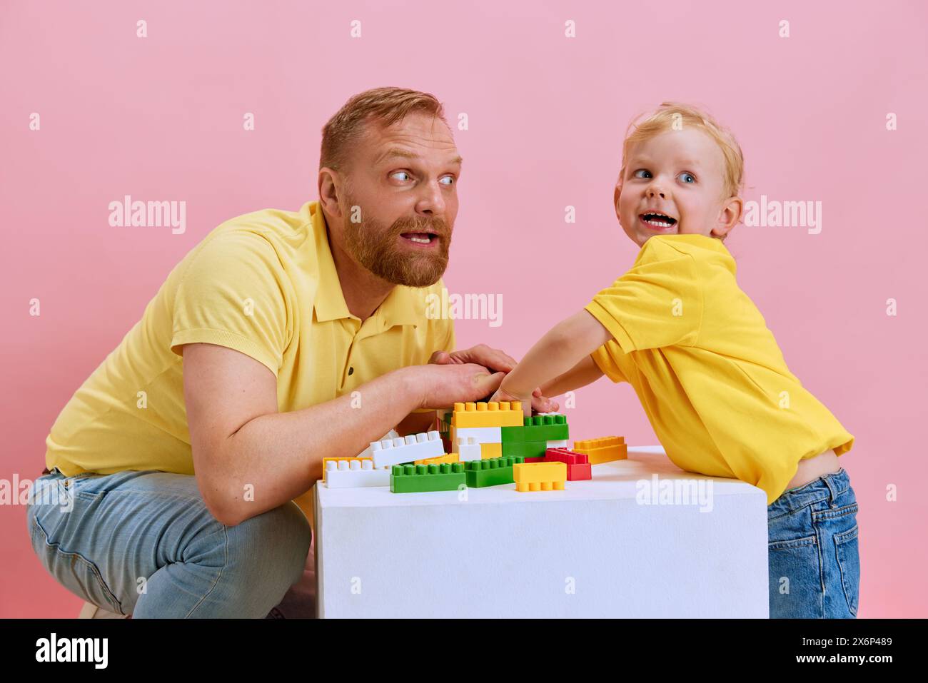 Father guides his little boy, son in building toy with vivid blocks ...