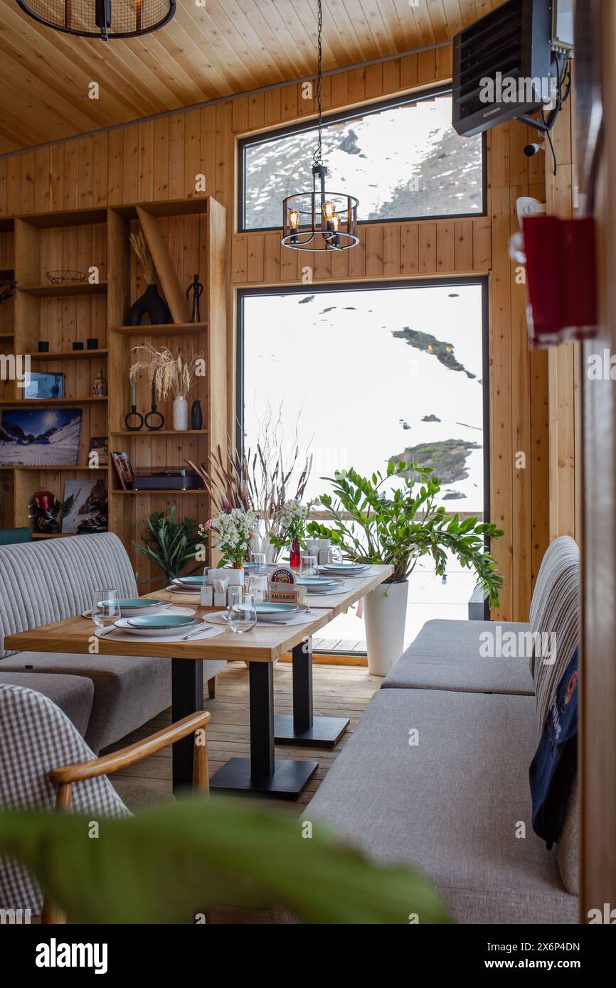 A rustic eatery with wood paneling, large windows, snowy landscape view ...