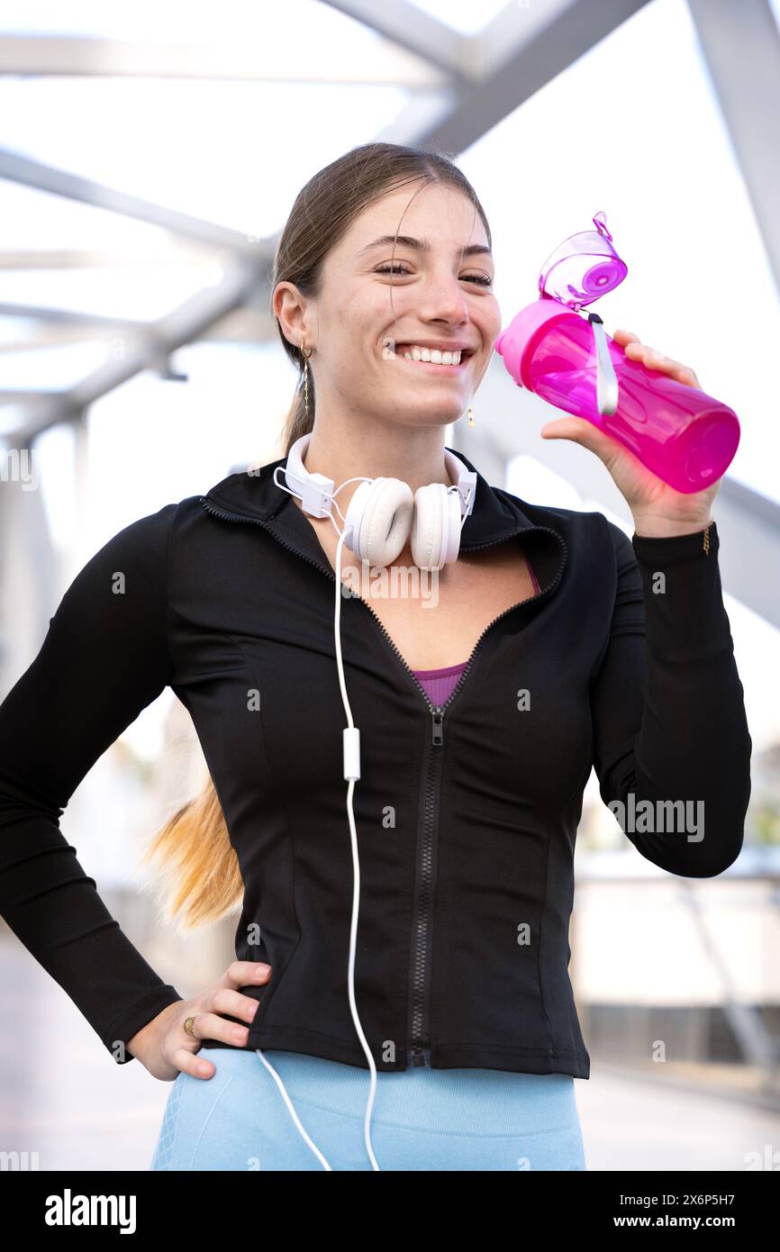 Vertical portrait runner girl drinking water from a sports bottle ...