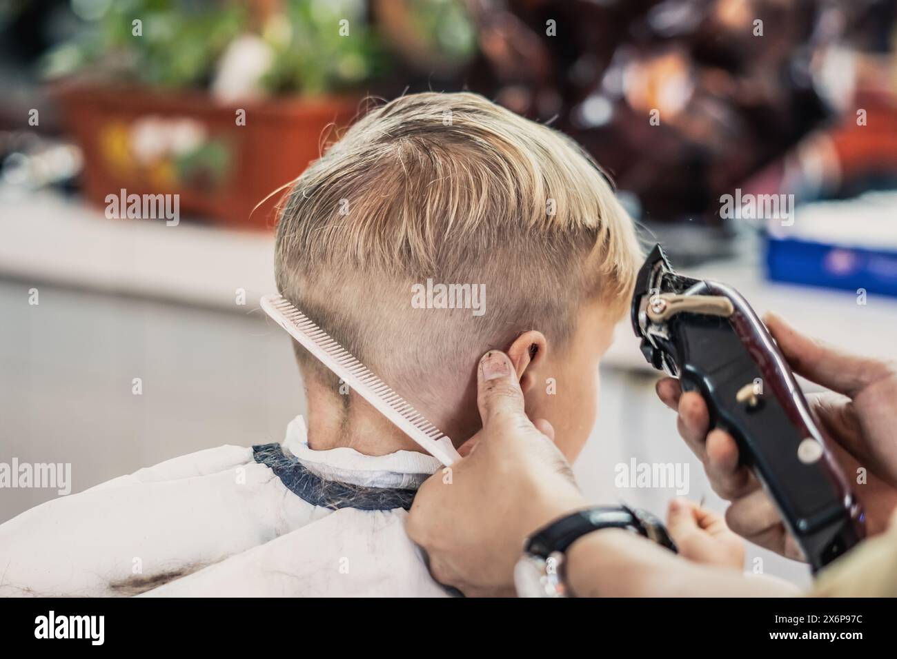 Barber shop blond boy customer. Hairdresser hand electric tool clipper ...