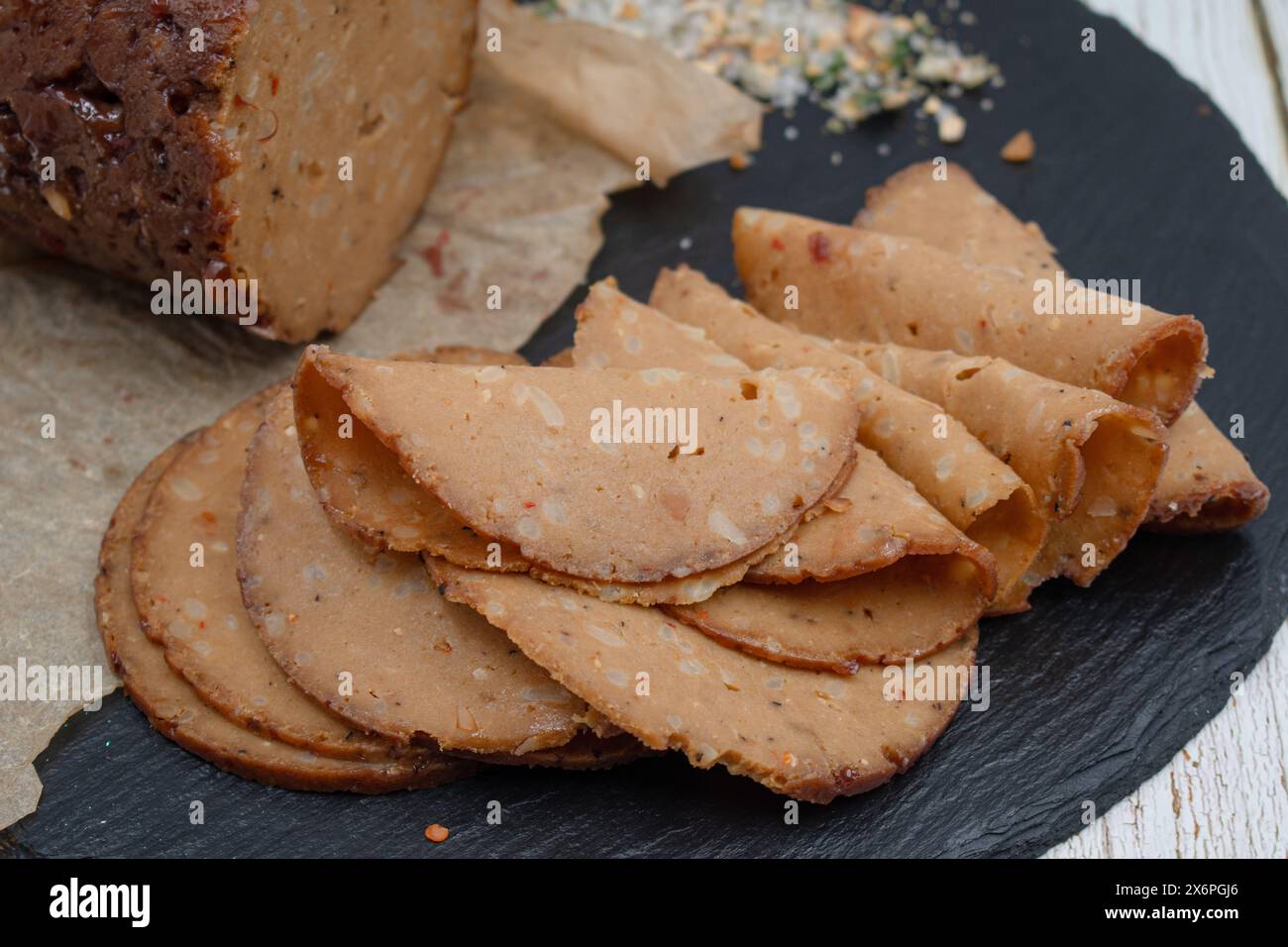 Seitan shaped and cooked in ham press, sliced on slate board. Vegan ...
