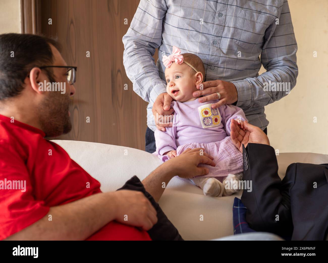 uncle and grandfather holding his brothers daughter feeling playing ...