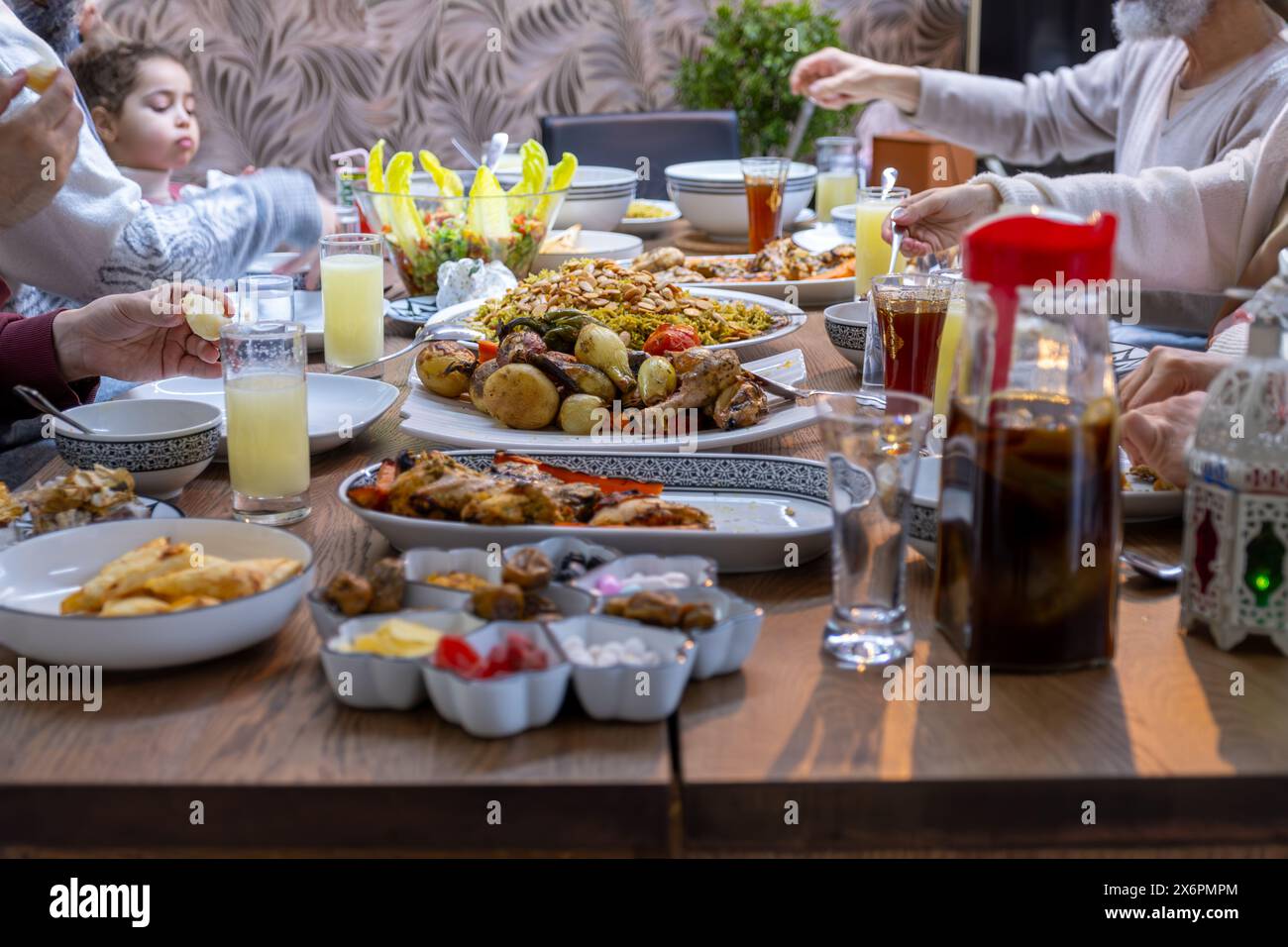 A Muslim family gathers around a rectangular table, sharing a ...