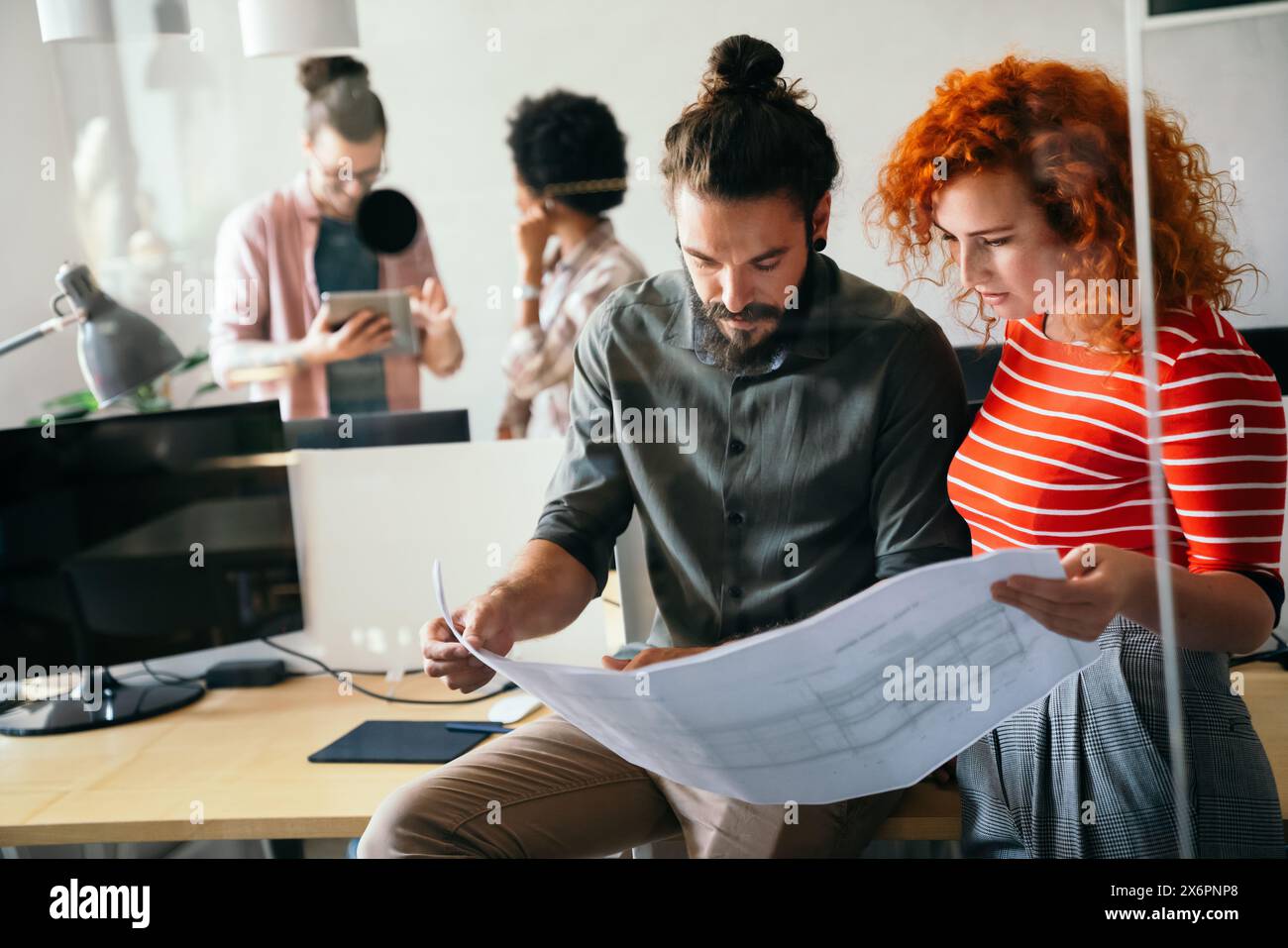 Engineers helping design work on blueprints, collaborate on structural ...