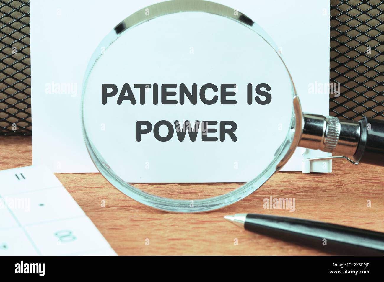 Concept words PATIENCE IS POWER through a magnifying glass on a white ...