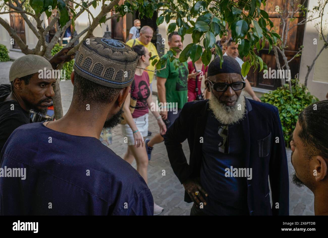 Muslims speak in front of their mosque as tourists, wearing Ernesto ...