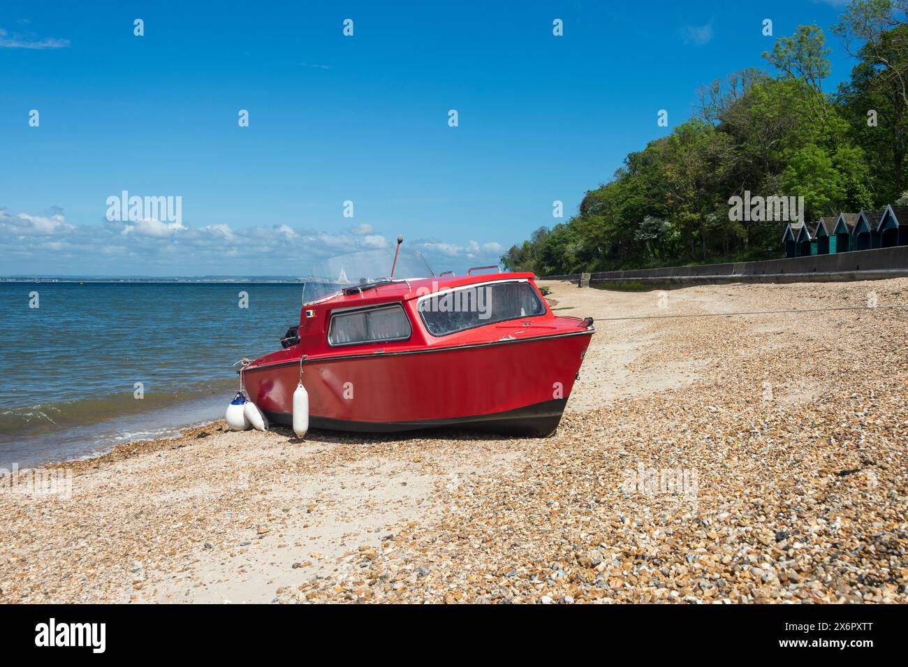 Small red classic motorboat moored on the beach at the Isle of Wight ...