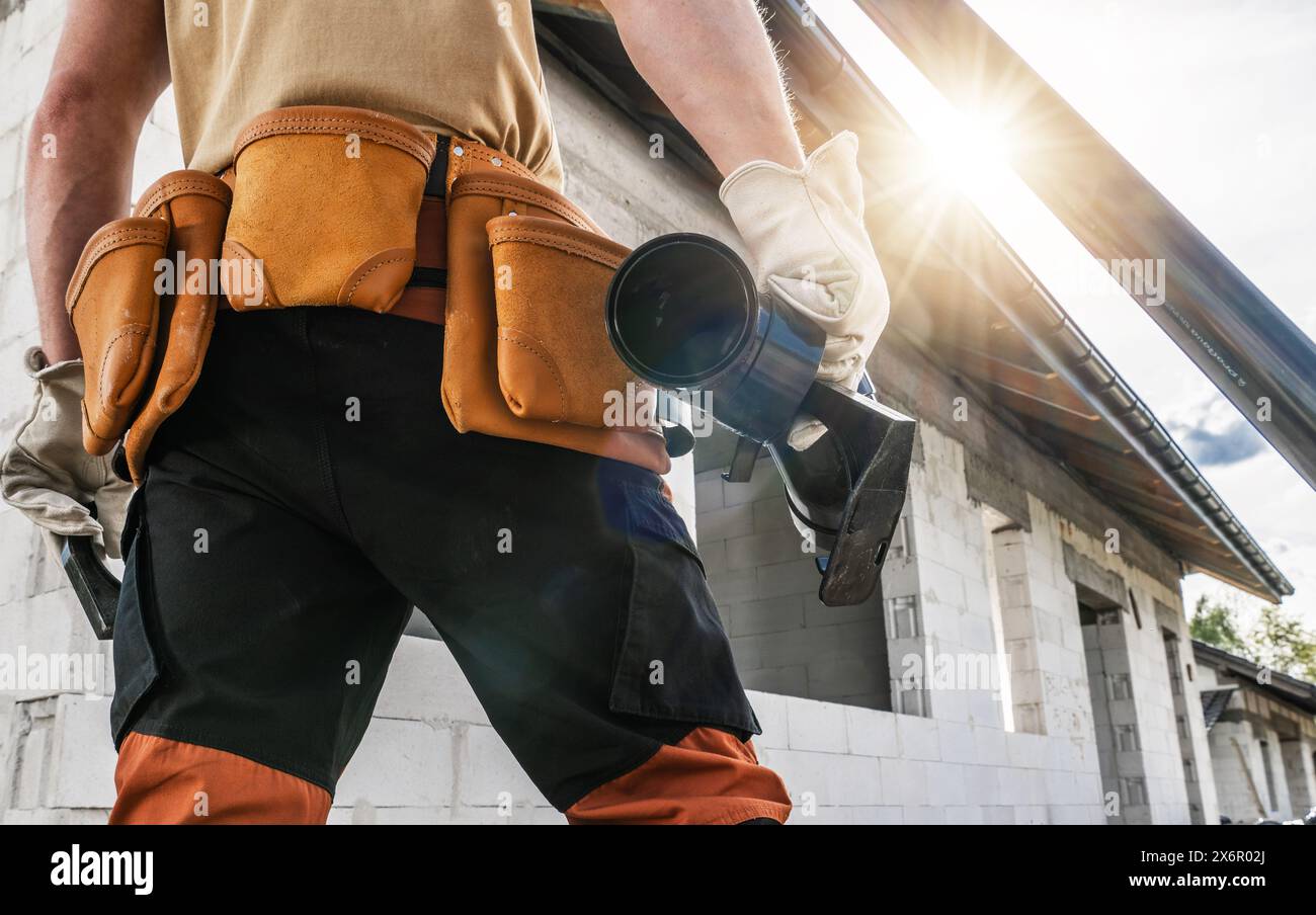 Construction worker wearing tool belt, holding piece of a gutter Stock ...