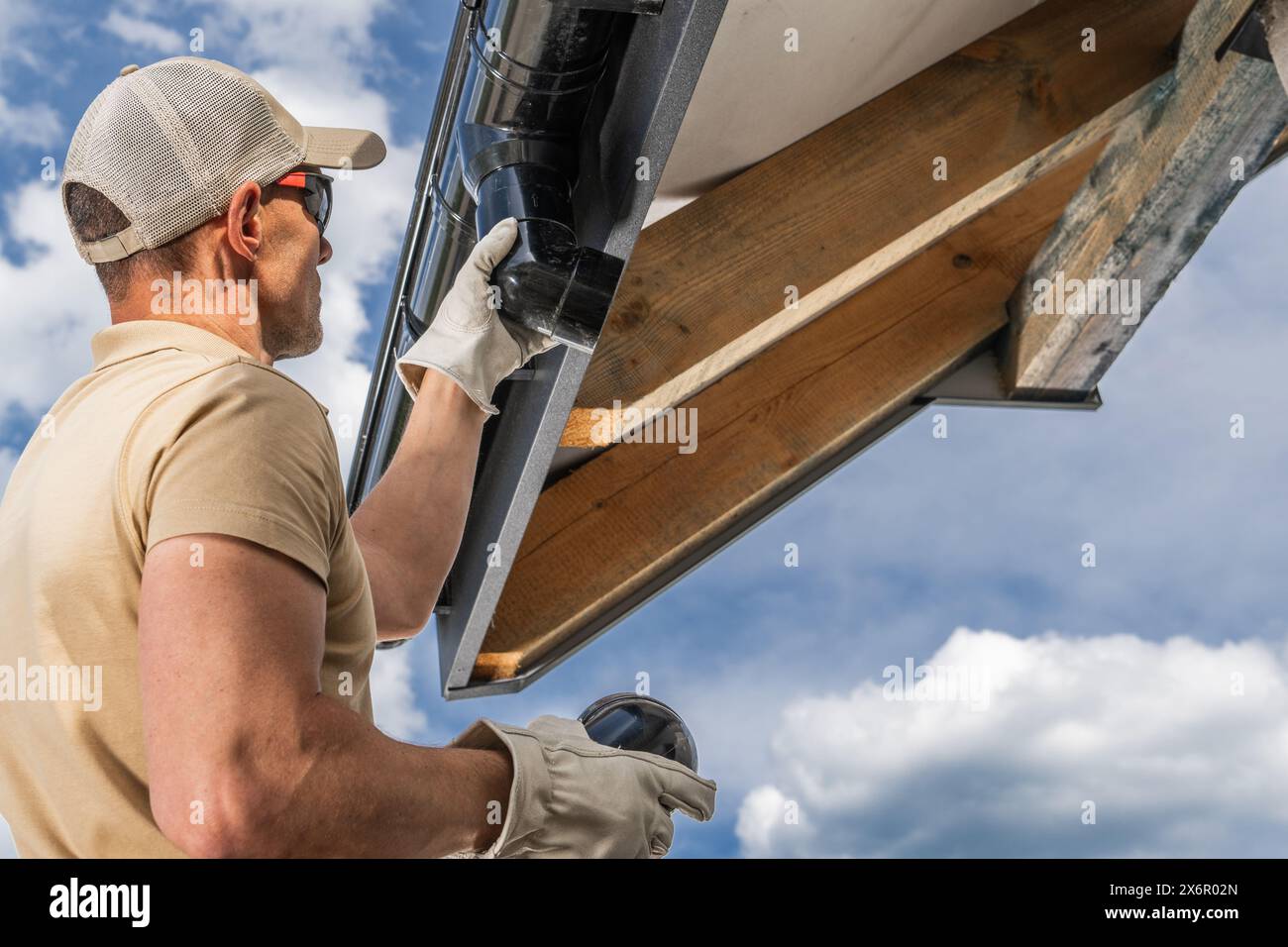 Man working on rooftop installing gutter system Stock Photo - Alamy