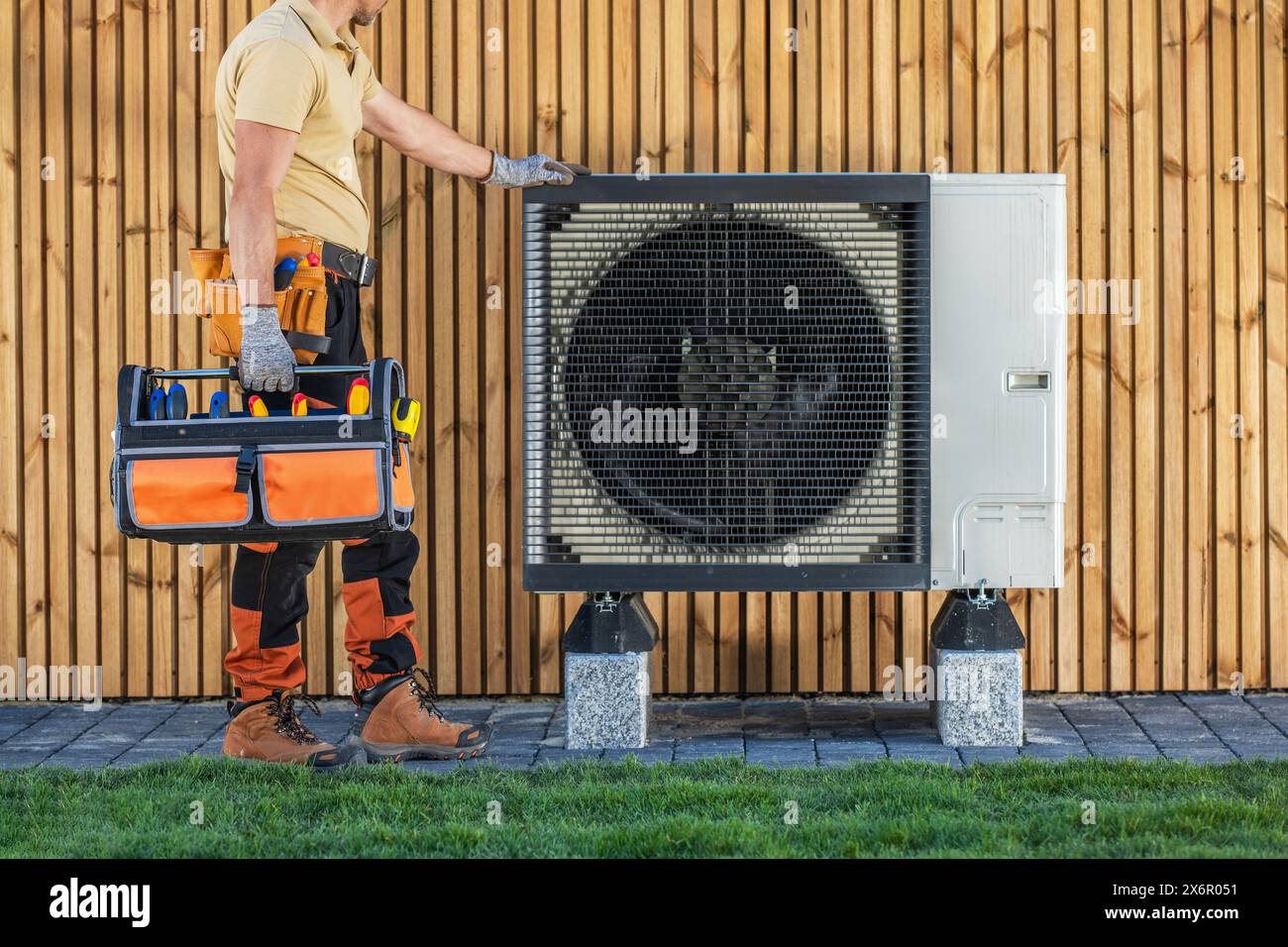 HVAC technician standing next to an air conditioning unit installed ...