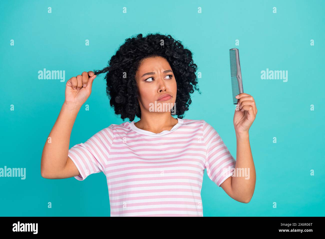 Photo of young upset lady in striped t shirt cannot untangle her hair ...