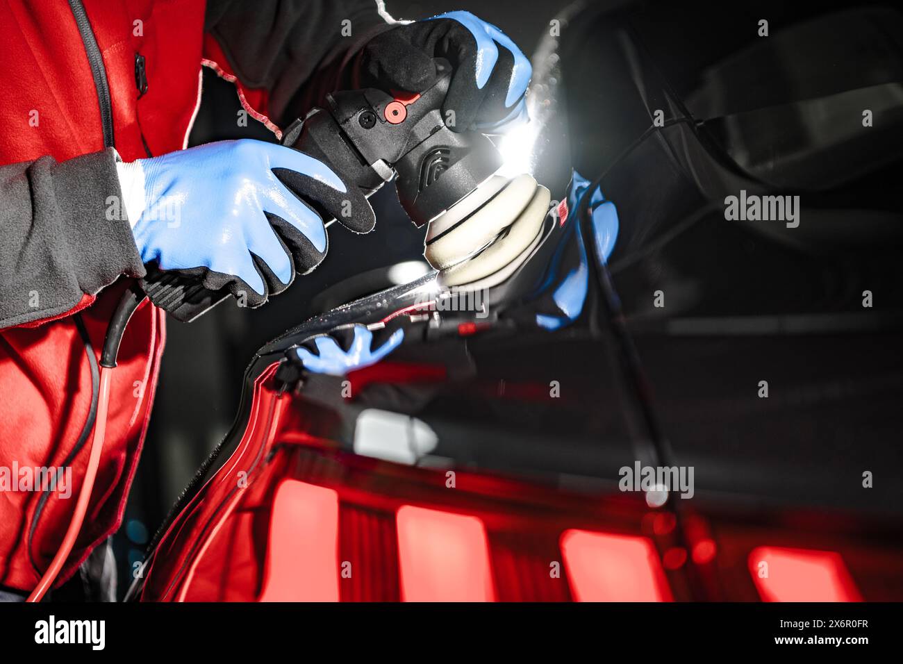 Automotive worker waxing and polishing car hood close up ...