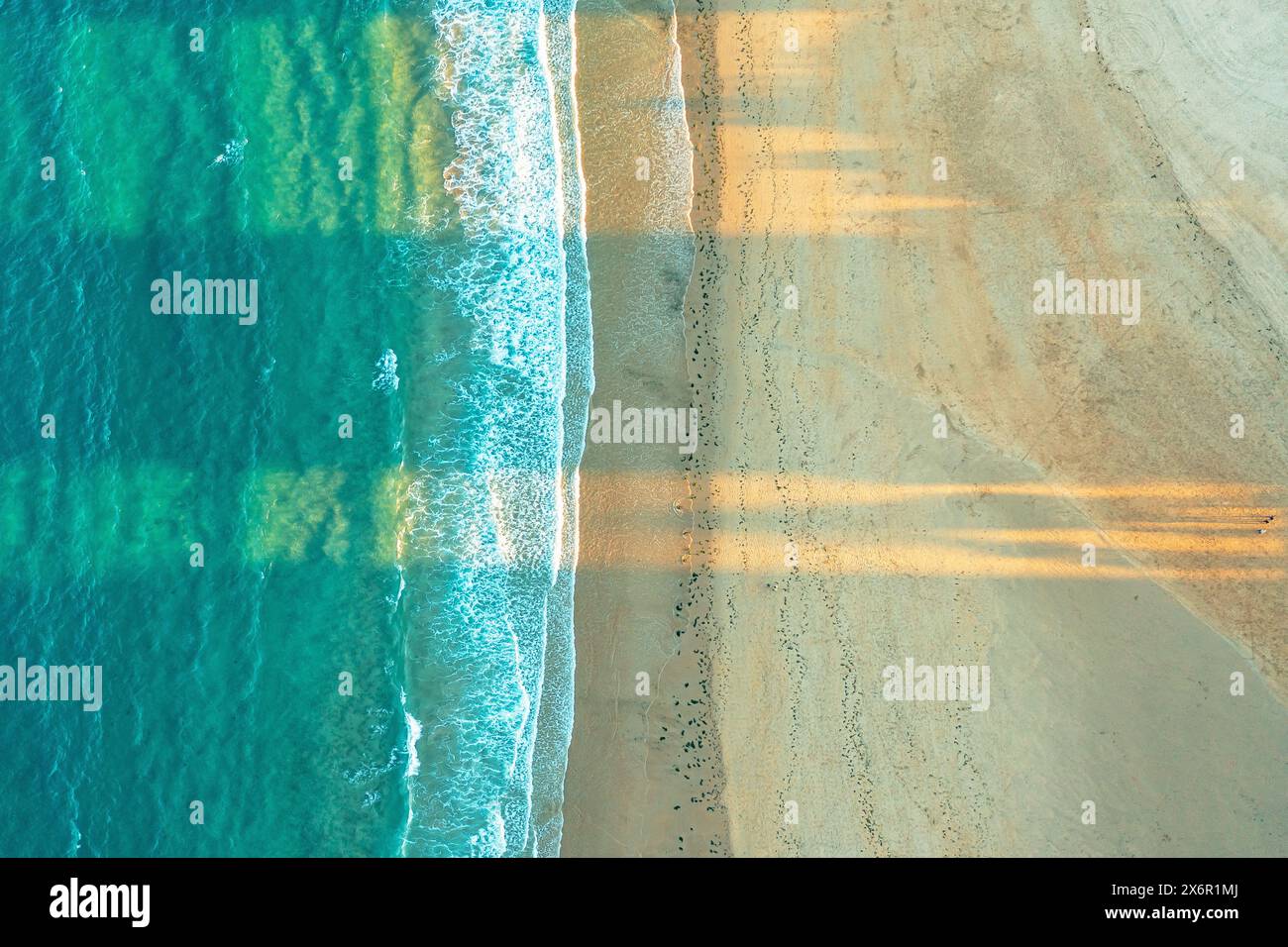 Top view of a sandy beach on the ocean shore. Yellow sand, blue water ...
